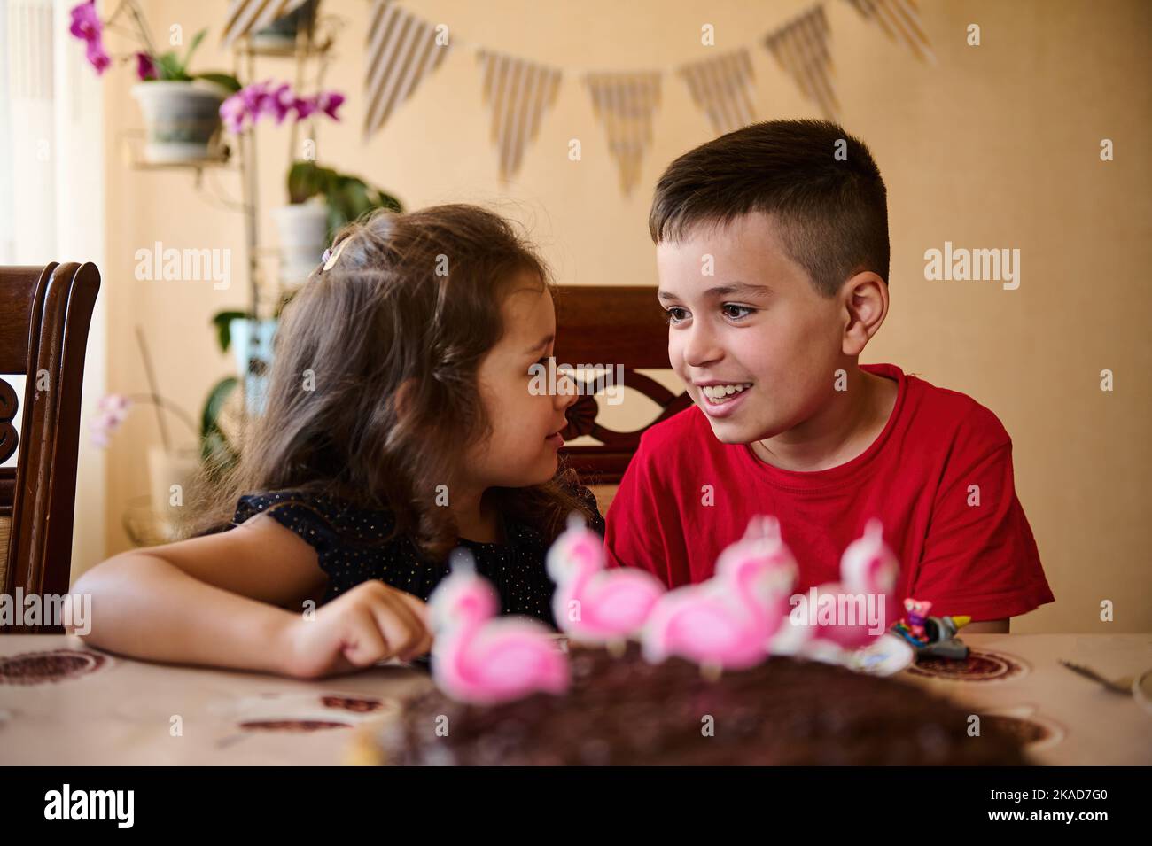 Charming kids, boy and girl, brother and sister having fun, sitting at table blurred birthday ...