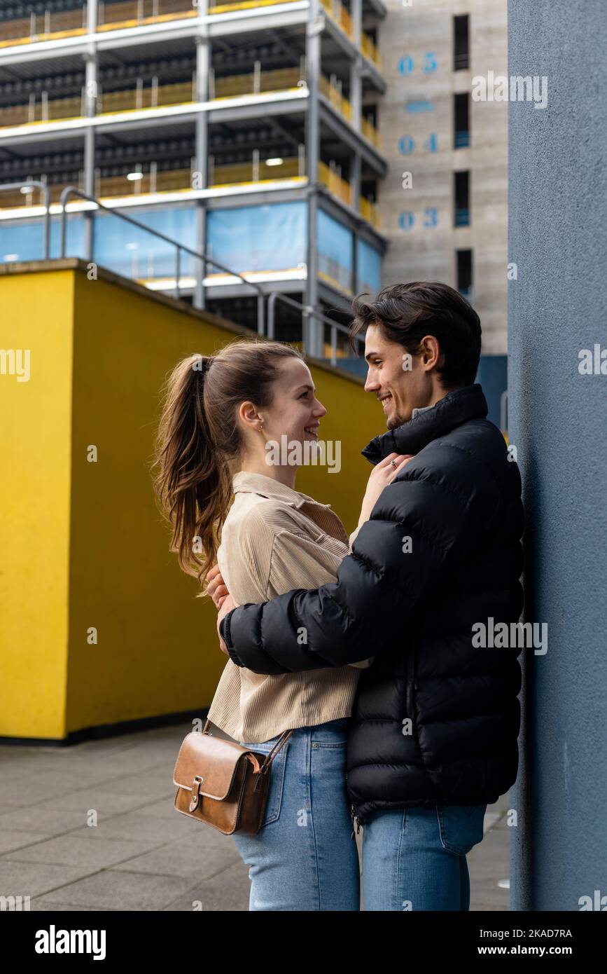 A side-view shot of a young couple standing face to face together ...