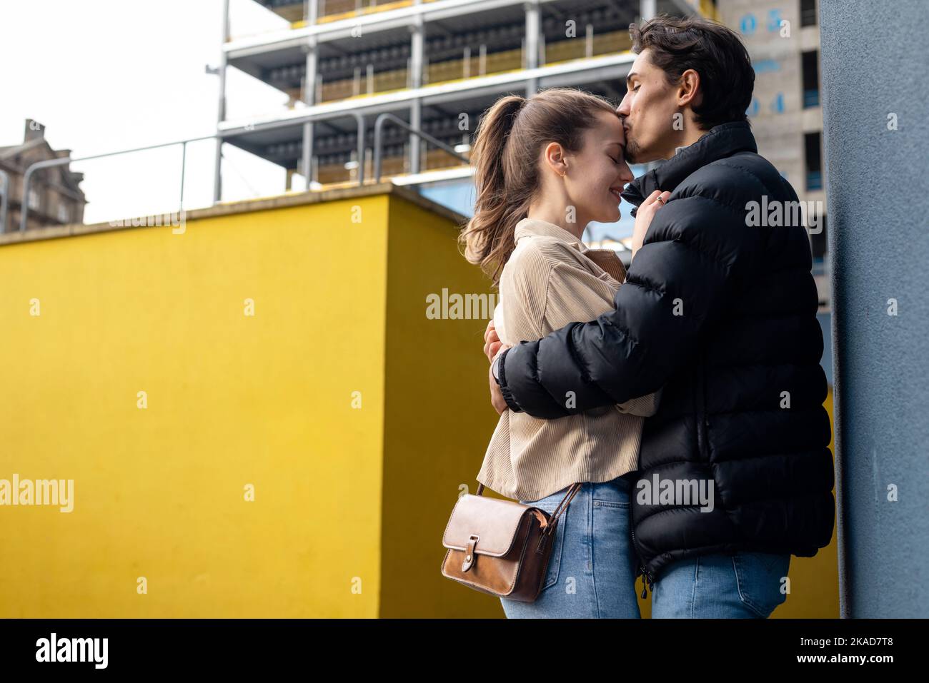 A side-view shot of a young couple standing face to face together ...