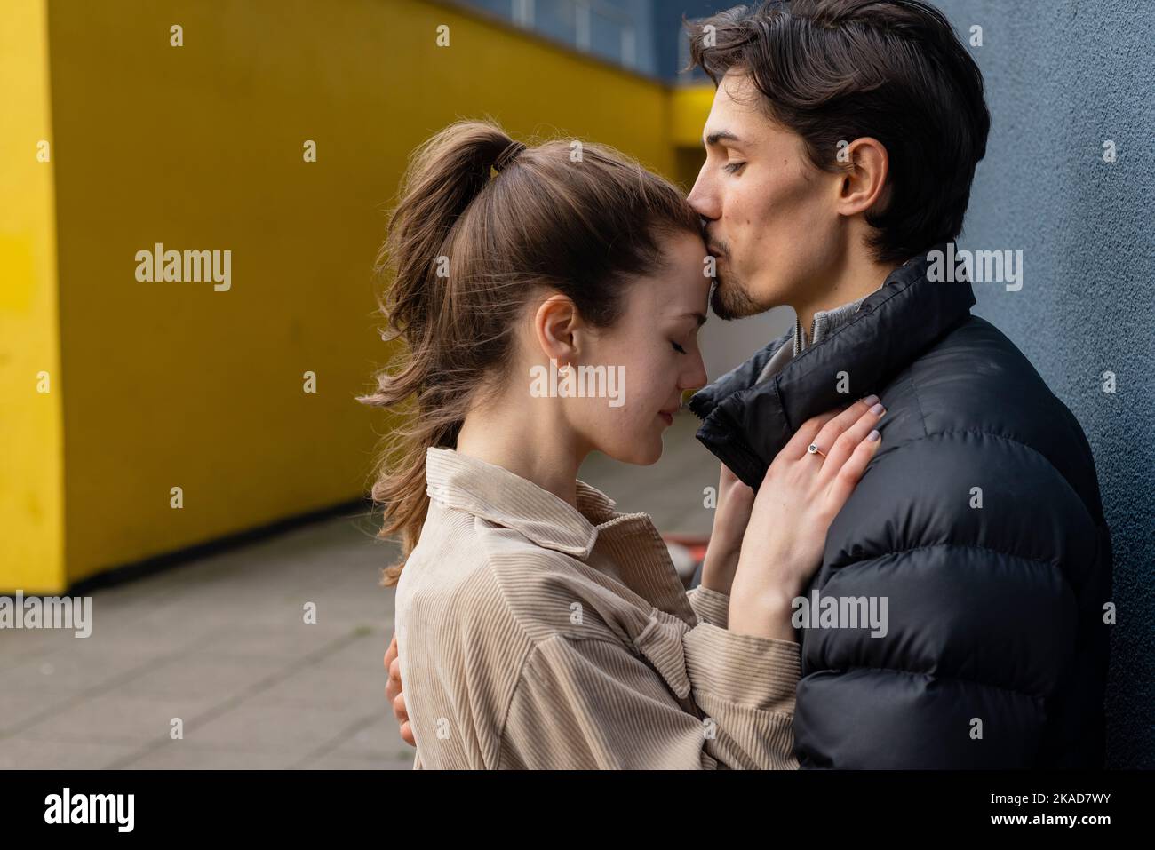 A side-view shot of a young couple standing face to face together ...