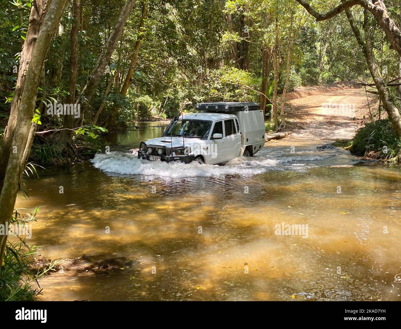 A white 4WD crossing a river in the rainforest in North Queensland ...