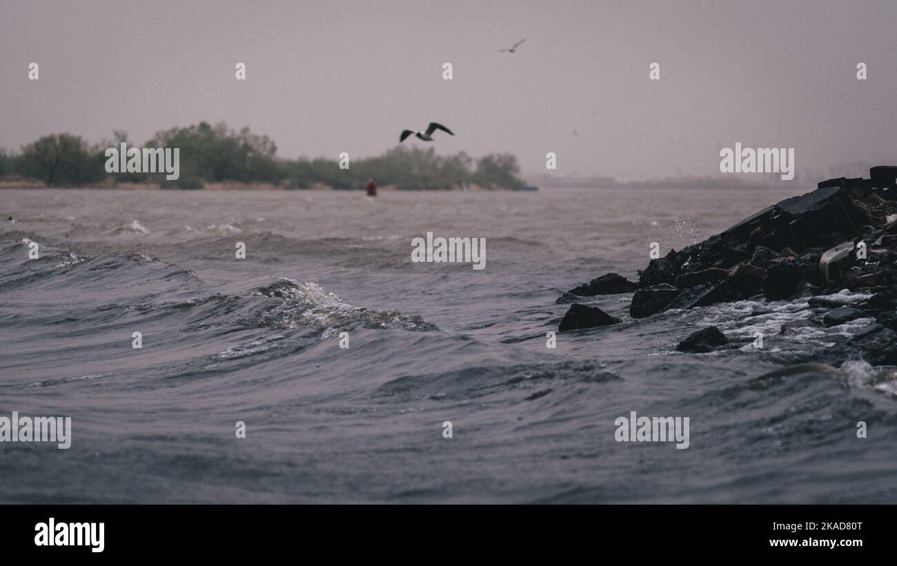 The waves crashing into rocks making foam on a windy day Stock Photo ...