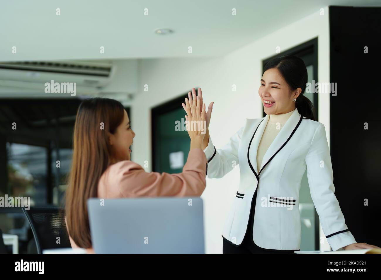 two female employees posing together after sales hit their targets ...