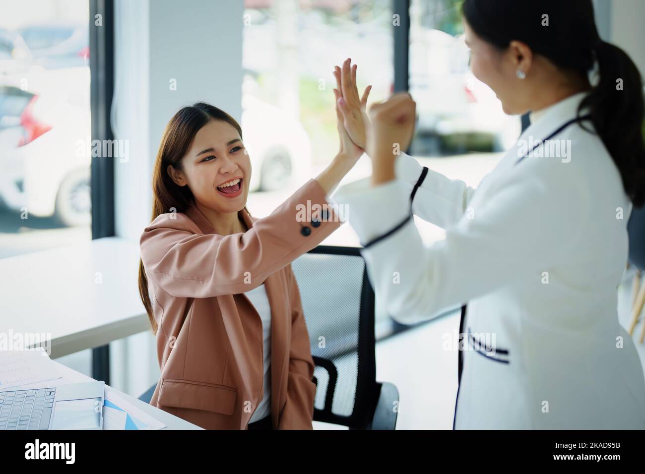 two female employees posing together after sales hit their targets ...
