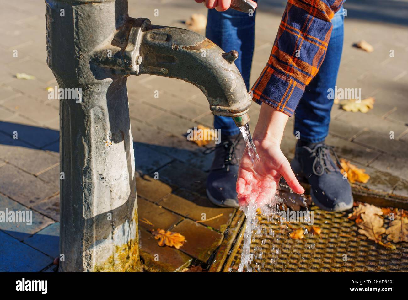 Female uses a drinking water hand pump to wash hands outdoors Stock ...