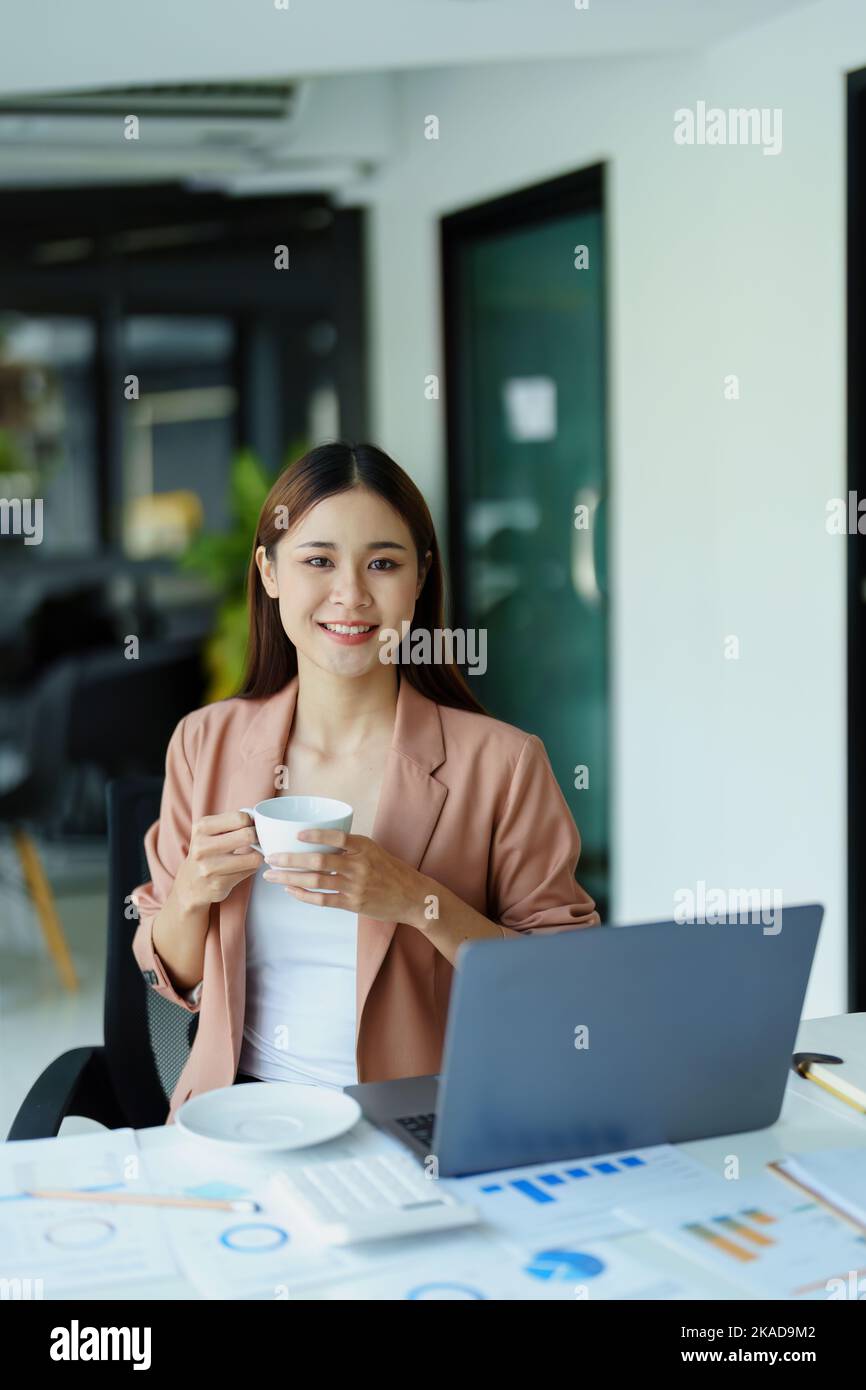 Portrait of a woman taking a coffee break while using a computer Stock ...