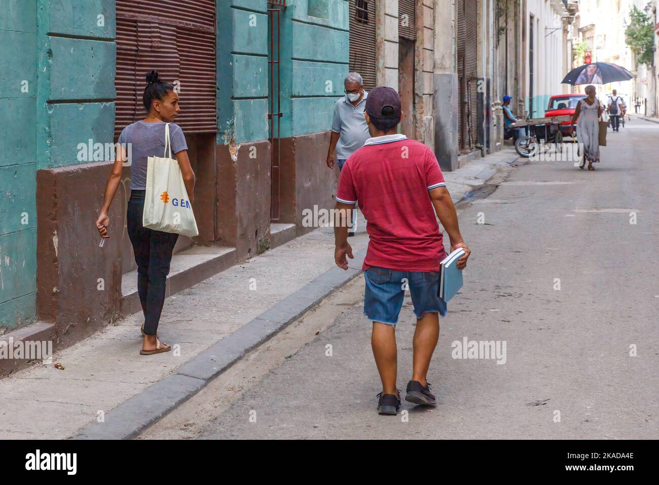 Cuban people's lifestyle while walking on a city street. A man carrying ...
