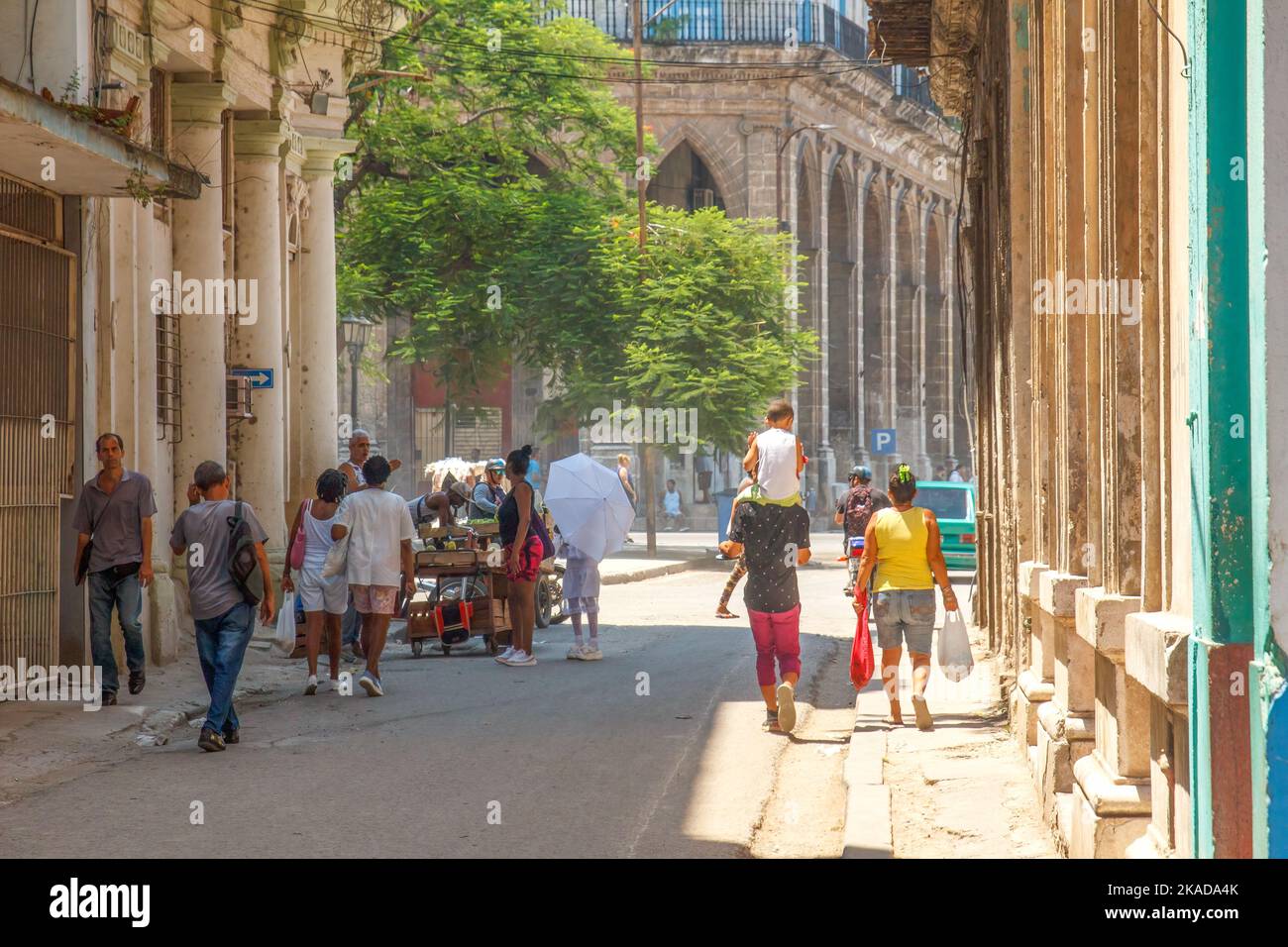 Cuban people's lifestyle while walking by a street vendor with a cart ...