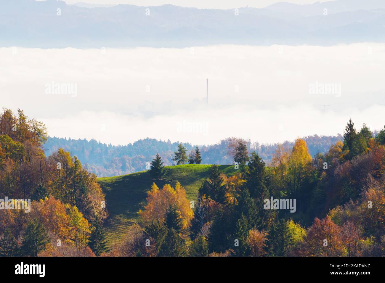 Beautiful hillside in the colors of autumn, city in fog visible in ...