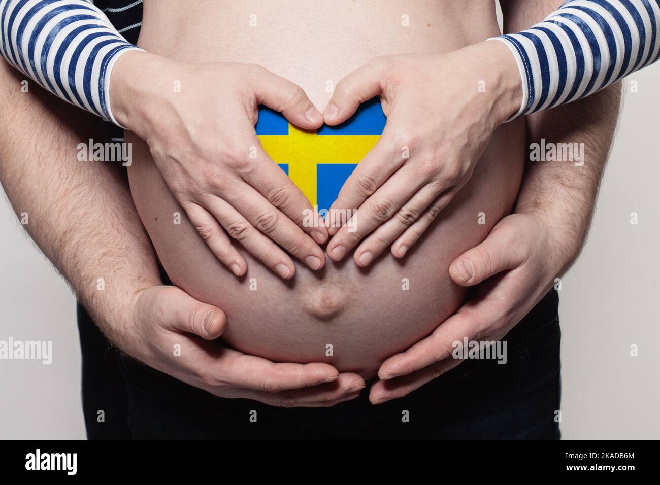 Swedish family concept. Man embracing pregnant woman belly and heart ...