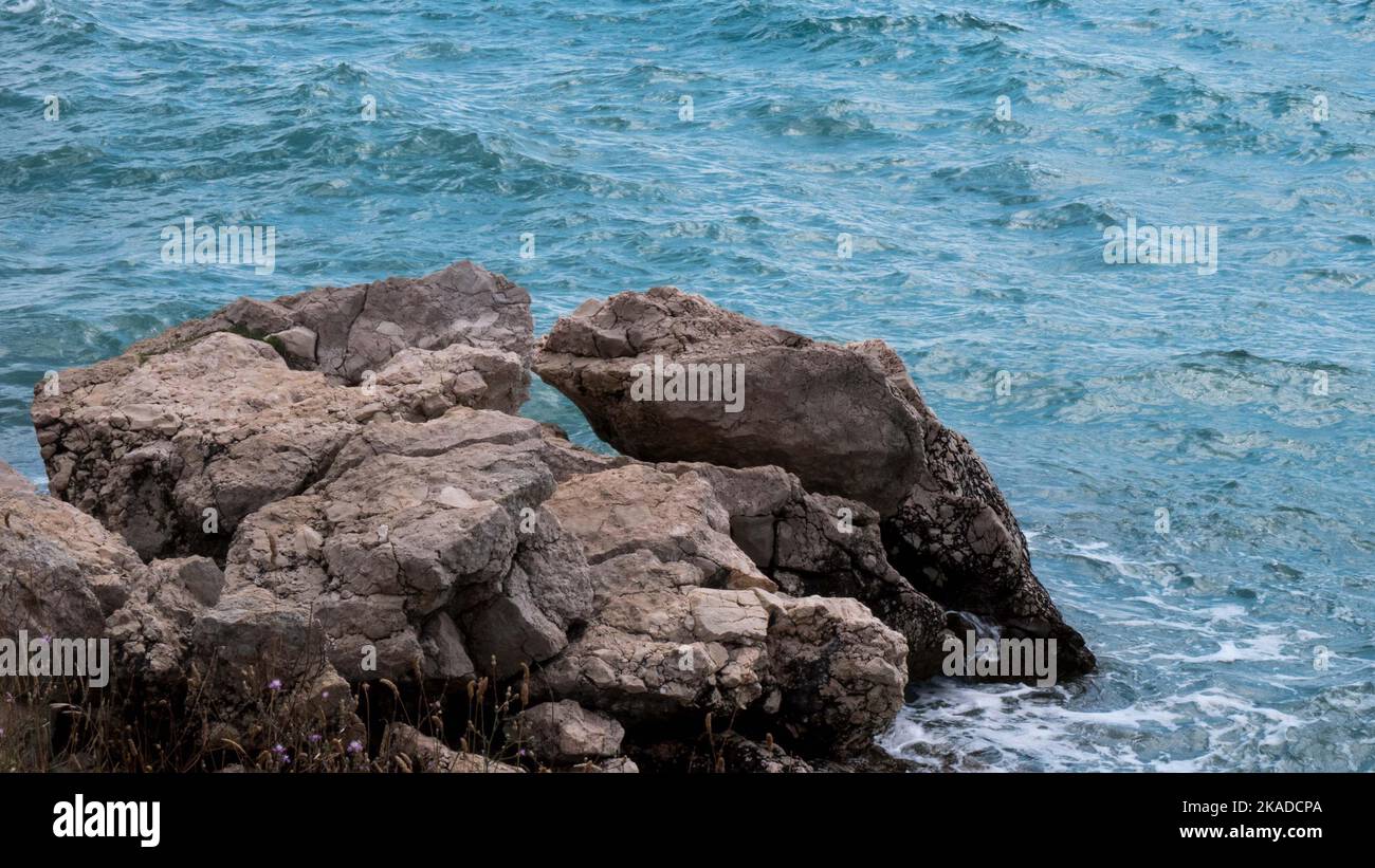 A bunch of dark brown rocks in foamy blue water Stock Photo - Alamy