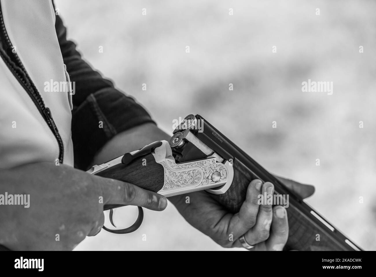 A grayscale shot of a man holding a double-barrel gun against a blurred ...