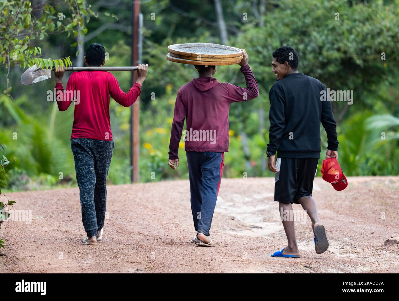 Three young men walking on the road with tools. Tepequém, Roraima State ...