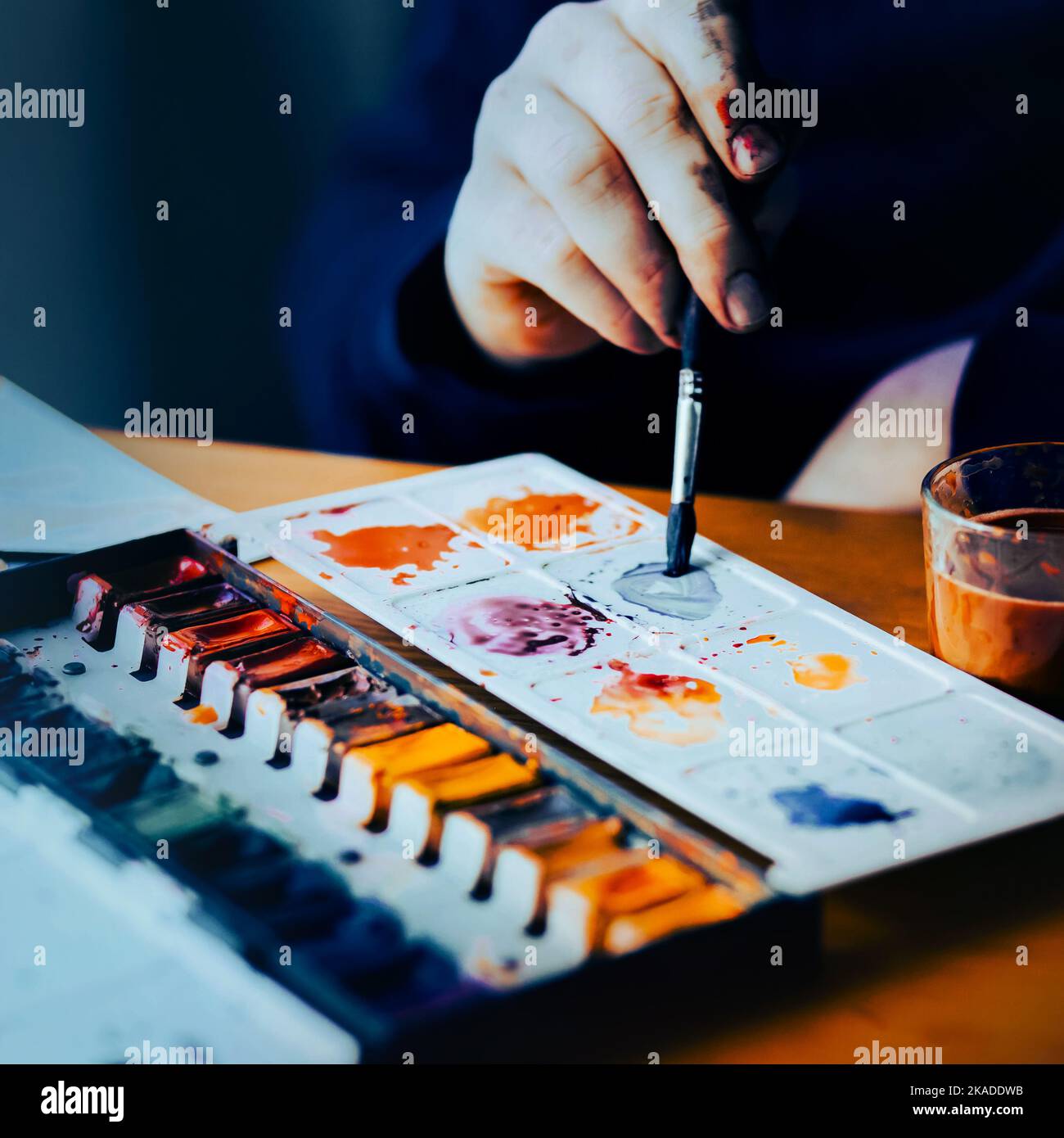 The artist mixes watercolor paints on the palette with a paintbrush ...