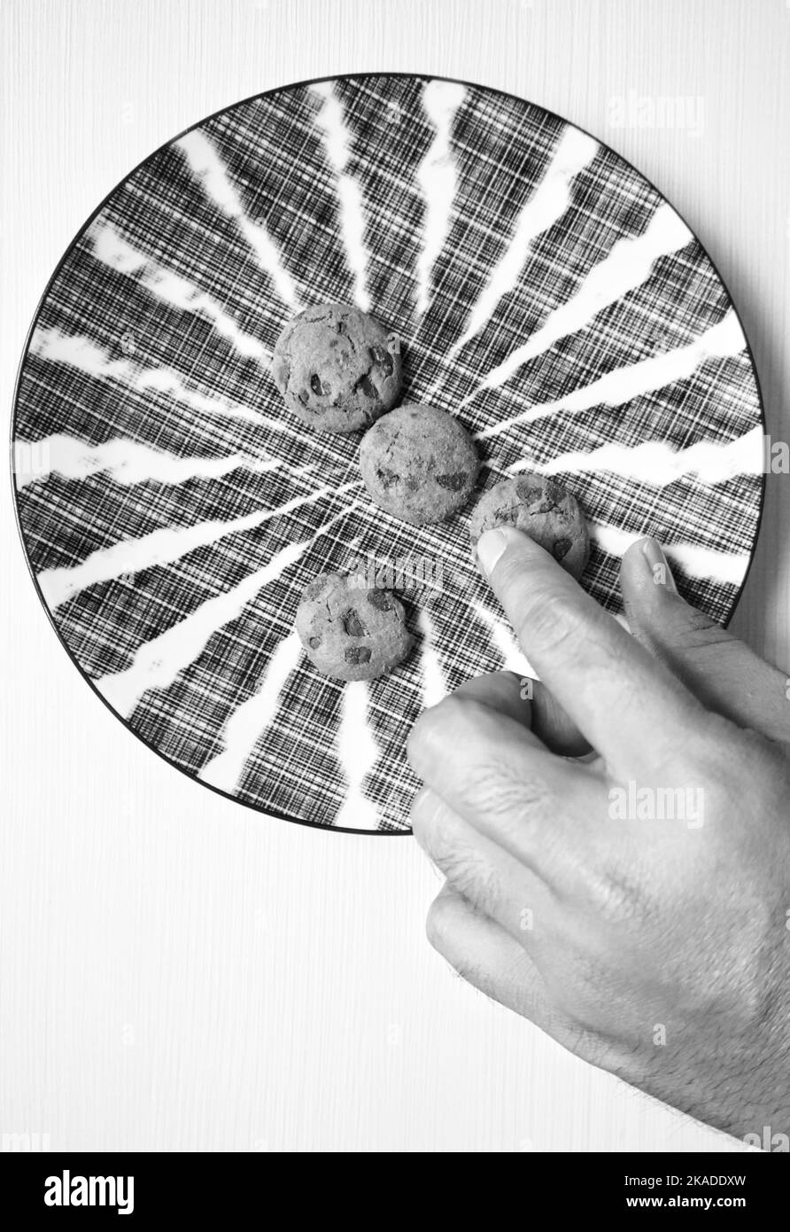 A grayscale of a hand taking a cookie from a plate Stock Photo - Alamy