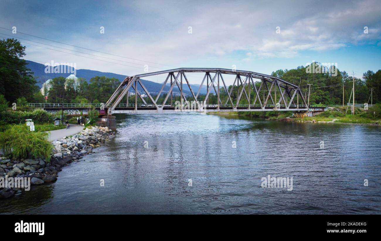 A metal bridge over a river on a cloudy day Stock Photo - Alamy