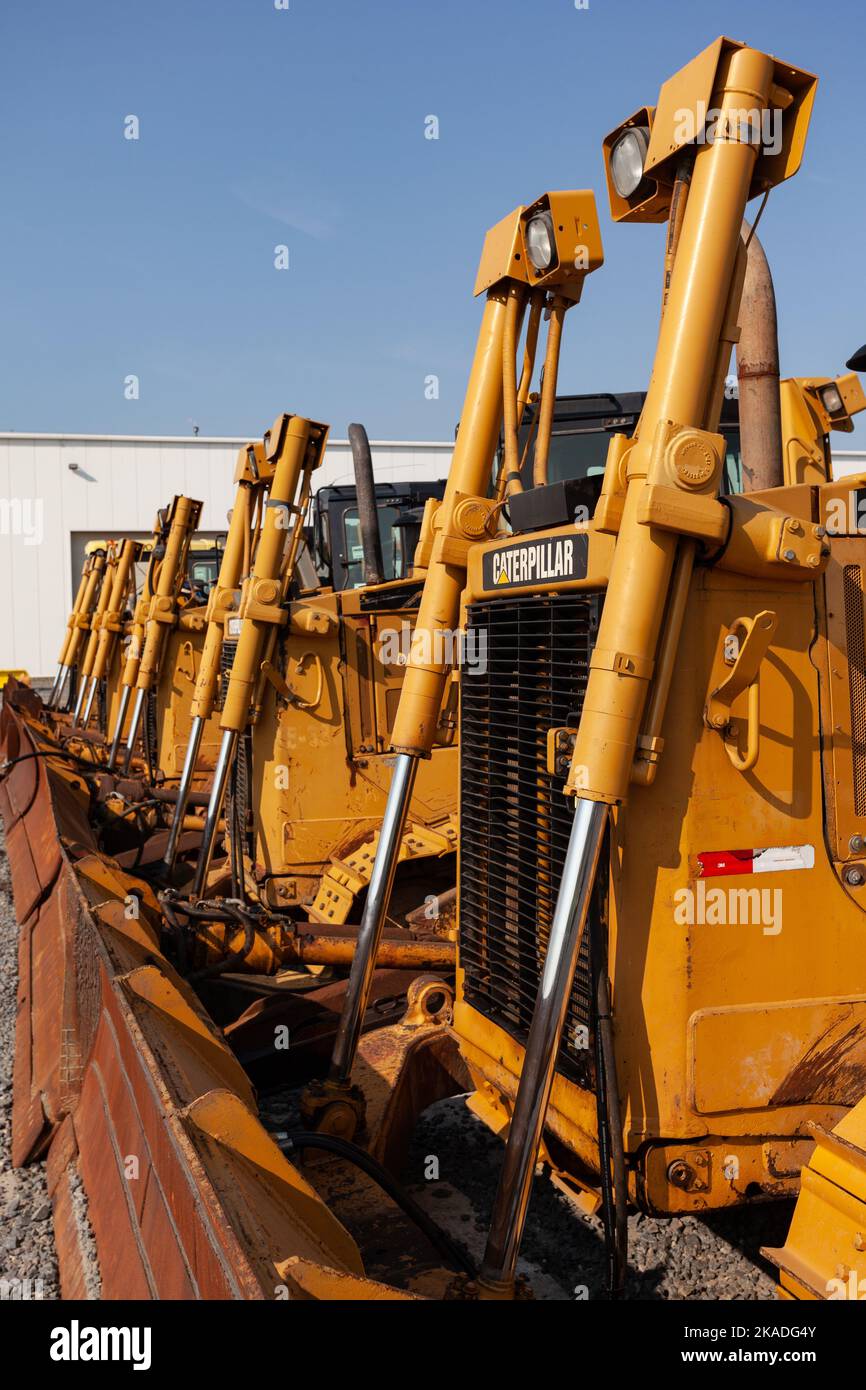 A row of bulldozers with blades and lift cylinders in a clear blue sky ...