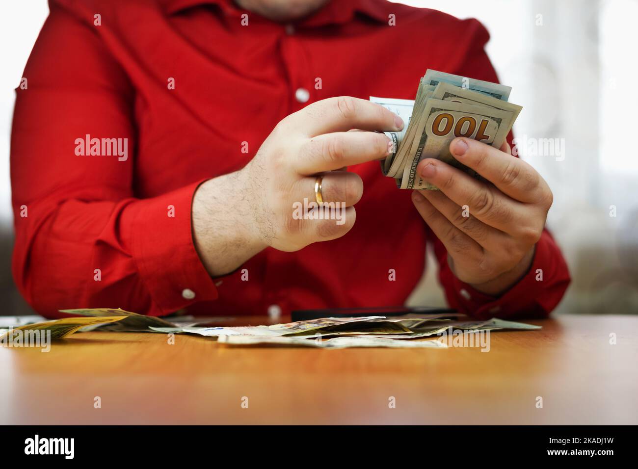 closeup of male hands counting a stack of US one hundred dollar bills ...