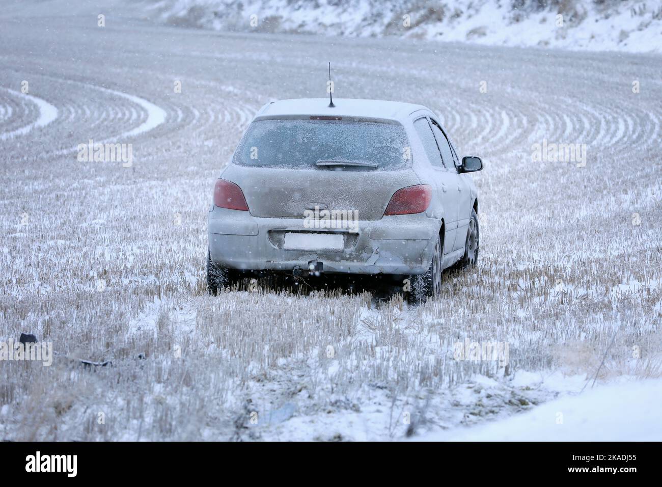 Compact grey car driven off slippery country road in winter and wrecked ...