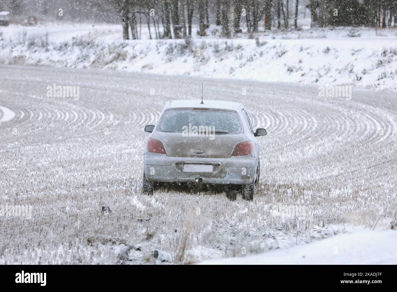 Compact grey car driven off slippery country road in winter, wrecked in ...