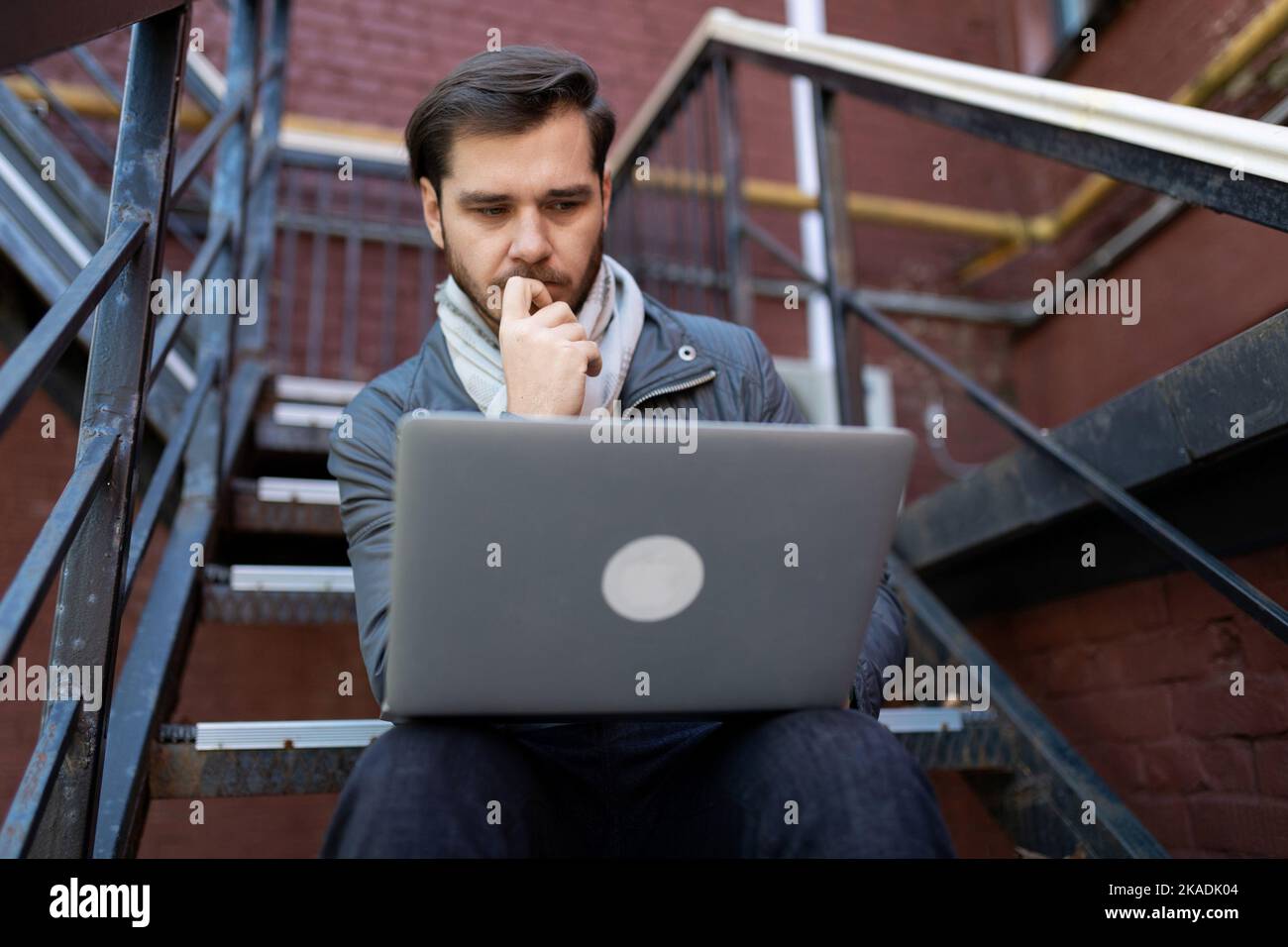 upset man in depression stands near the columns of a gray building ...