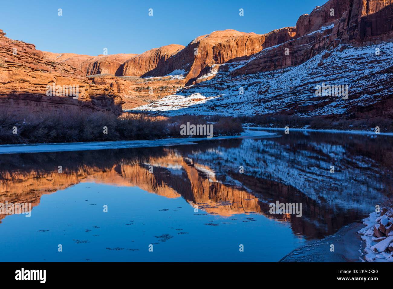 Orange sandstone cliffs reflected on the surface of the partially ...