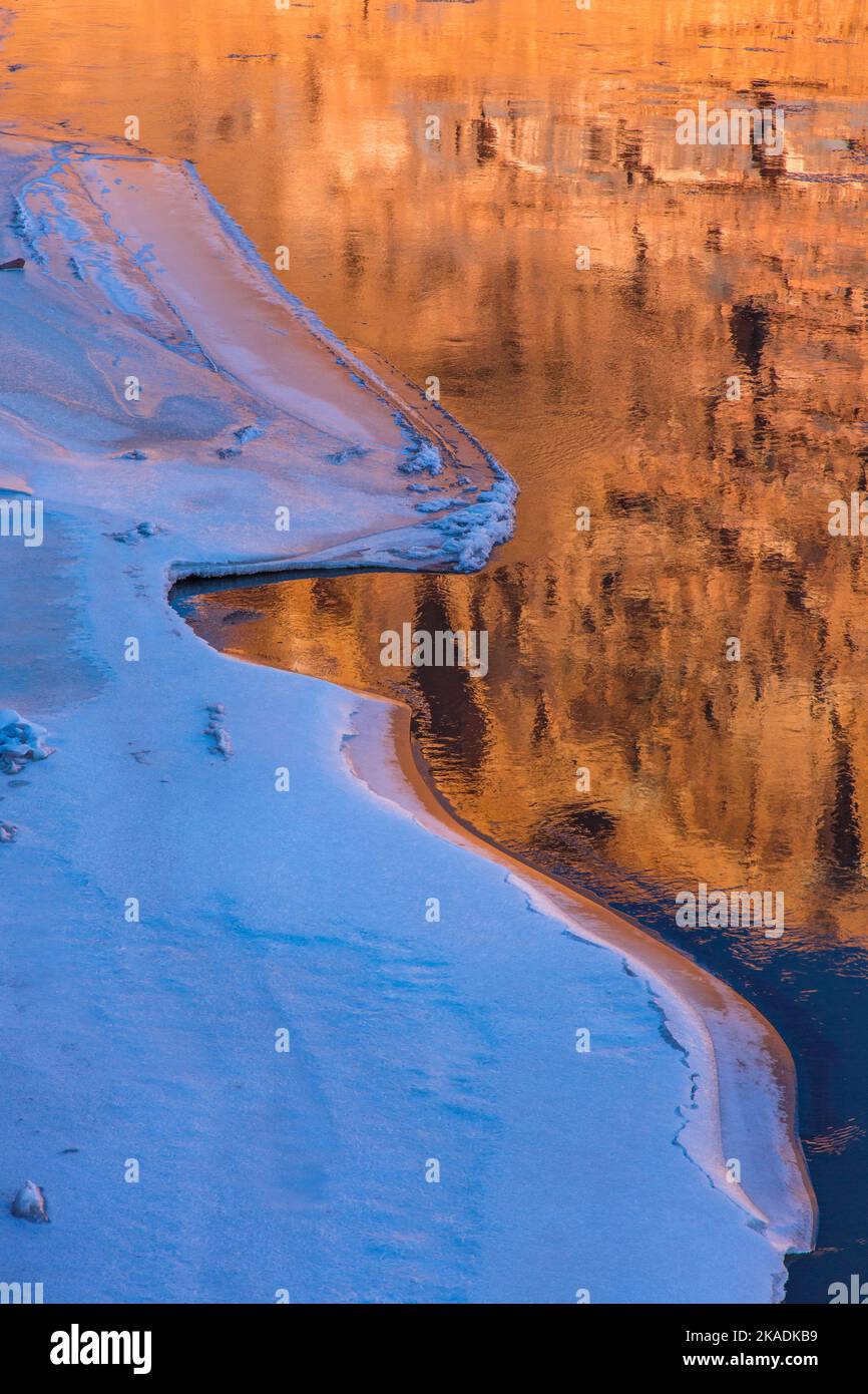 Orange sandstone cliffs reflected on the surface of the partially ...