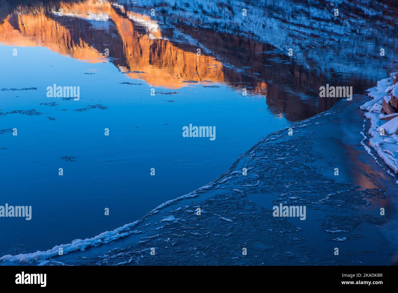 Orange sandstone cliffs reflected on the surface of the partially ...
