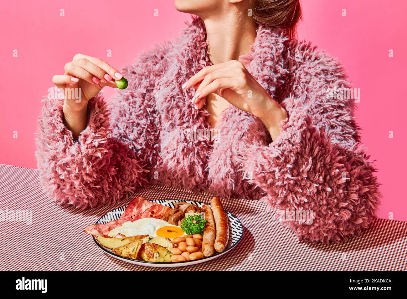 Woman in furry pink coat eating English breakfast with eggs, bacon ...