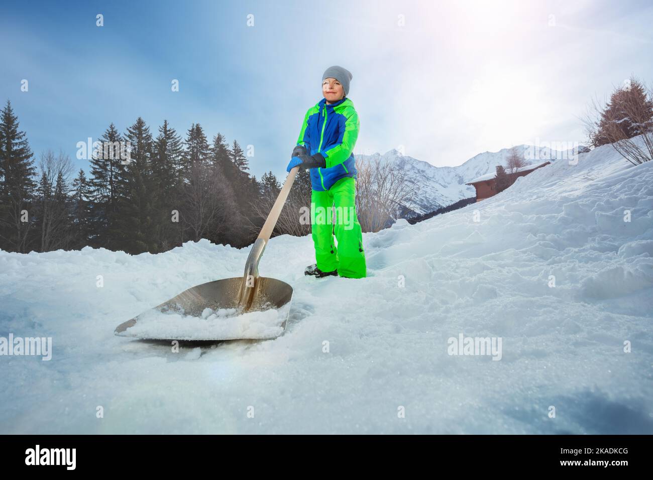 Boy clean path from snow at country house in with mountains Stock Photo ...