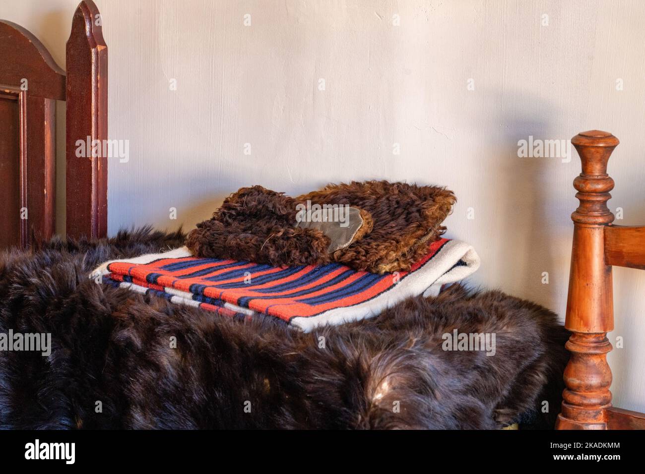 Buffalo hide mittens and bear skin r on a bed in a lodging room at the ...