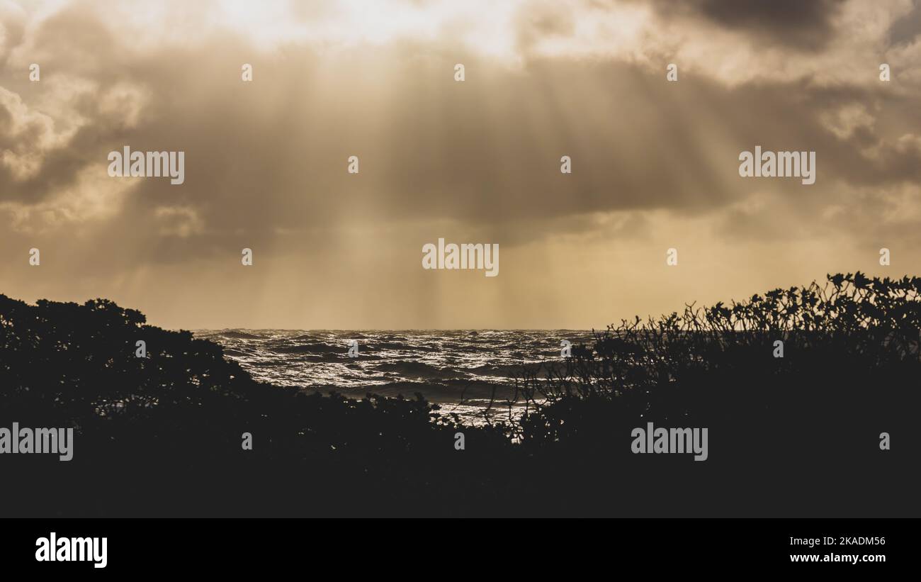 A beautiful shot of the sun hiding behind the clouds above a seascape ...