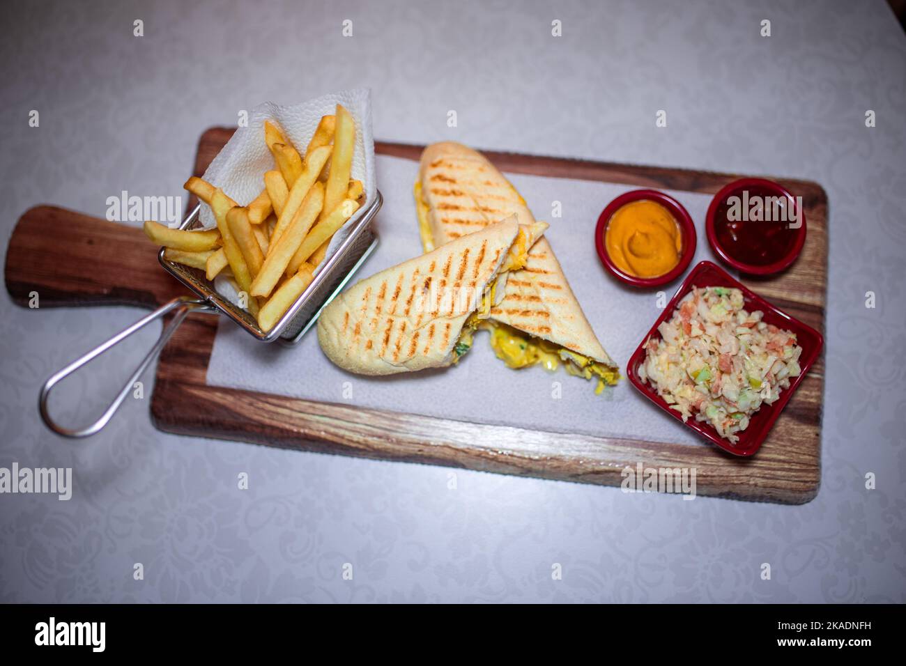 Panini sandwich sliced into two portions with french fries and a small ...