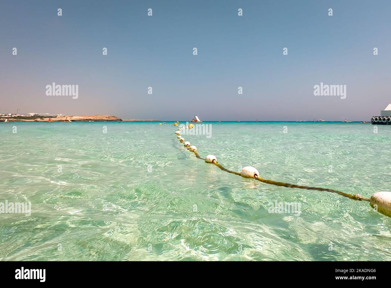 String of white marker buoys floating in the sea, watersport boats on ...