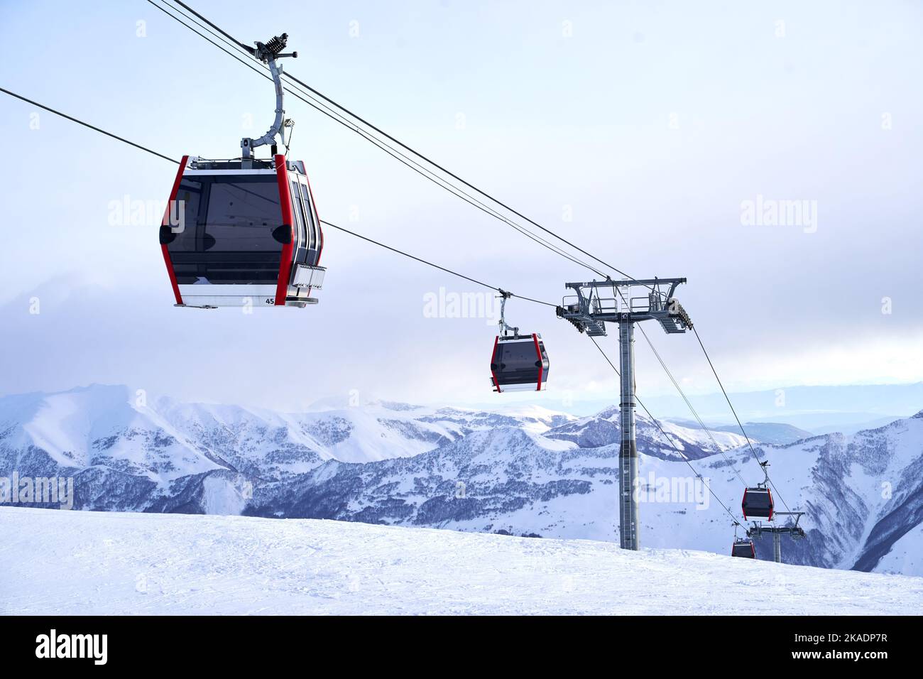 Cable car gondola at ski resort with snowy mountains on background ...