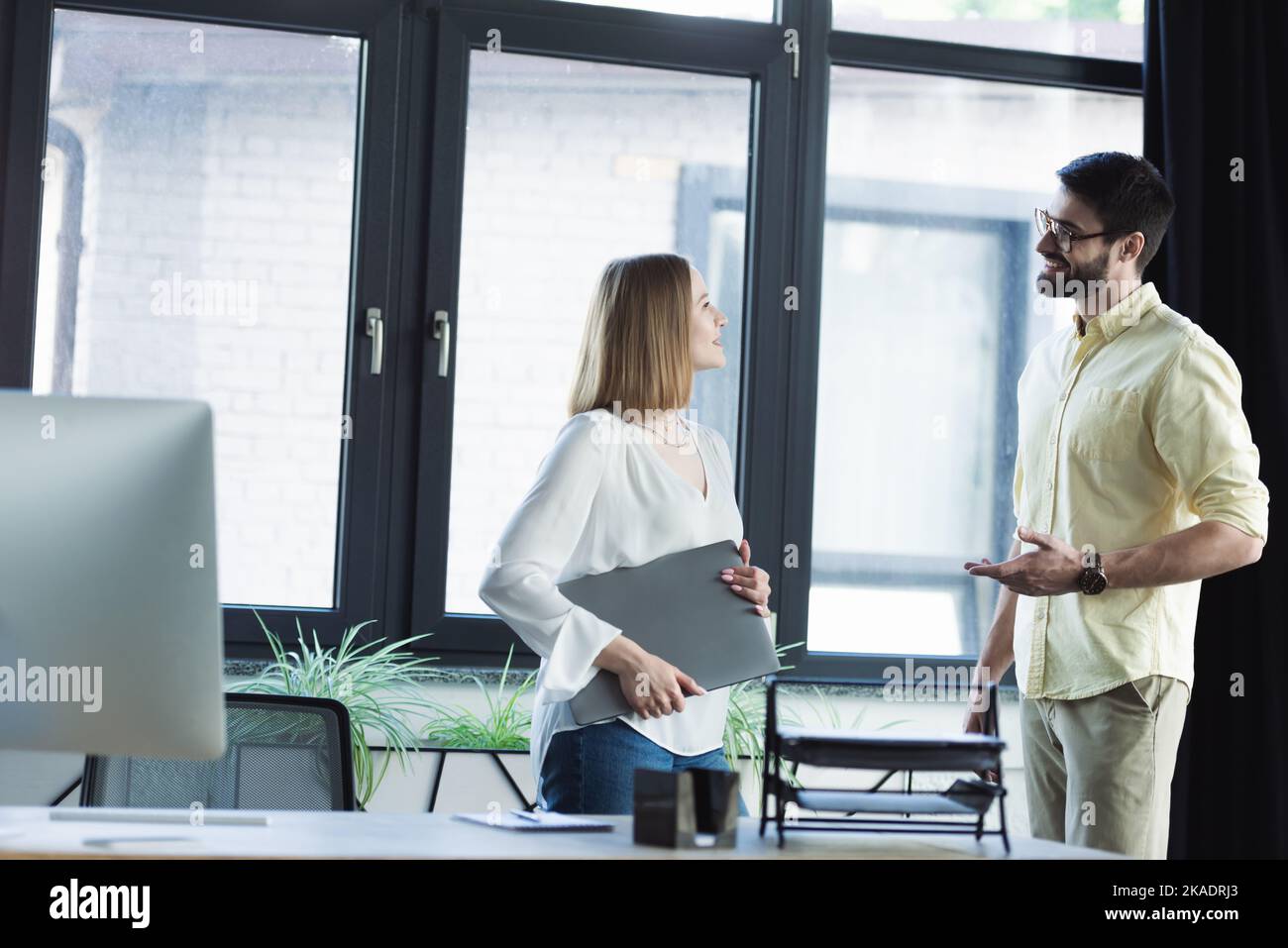 Positive manager talking to employee with laptop during internship in office,stock image Stock ...