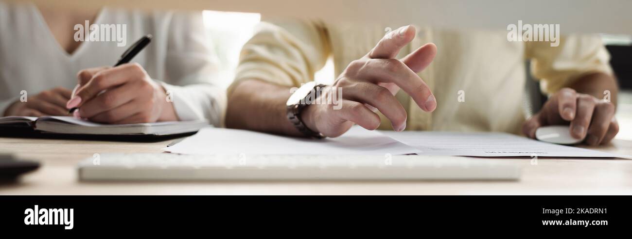 Cropped view of businessman pointing near intern writing on notebook in ...