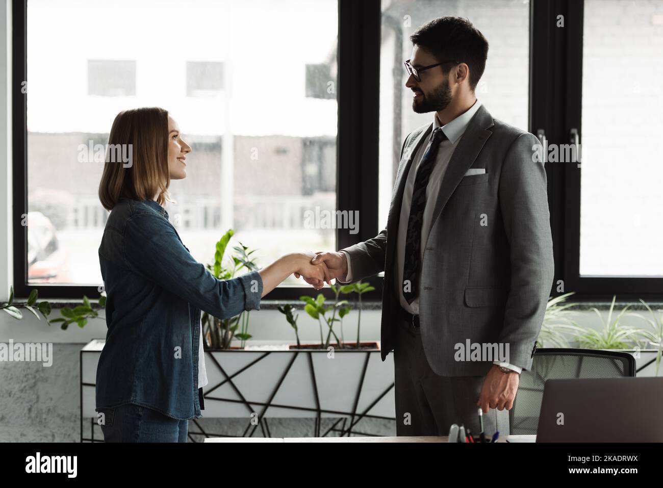 Side view of businessman shaking hand of happy job seeker in office ...