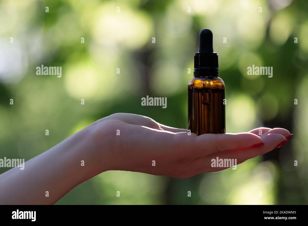 Hand showing essential oil bottle. Woman hand holding essential oil ...