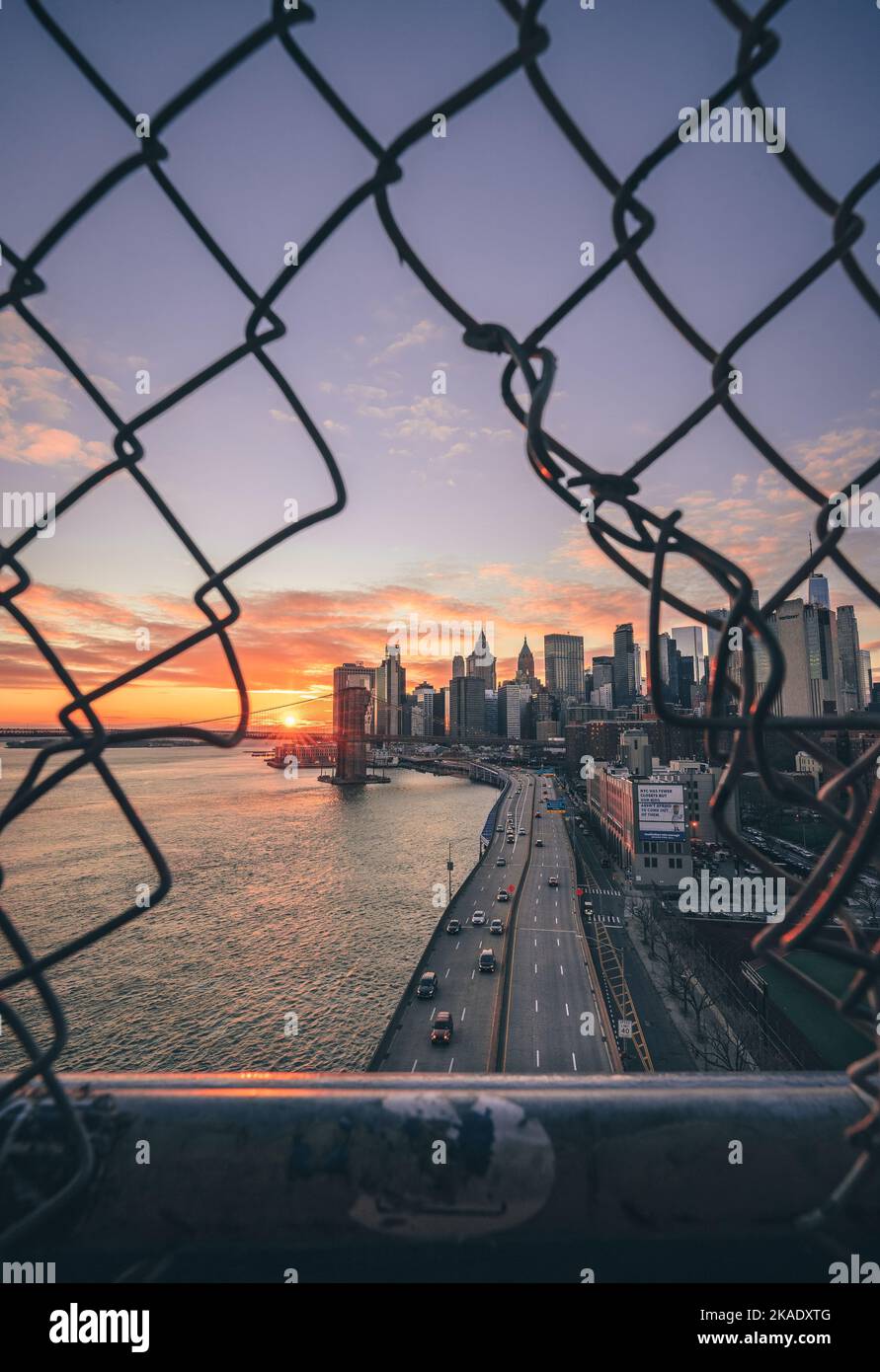A vertical shot of skyline of Manhattan during sunset through broken ...