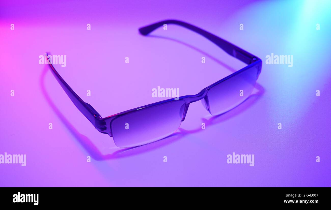 A closeup of rectangular optical glasses on a flat surface with a neon ...