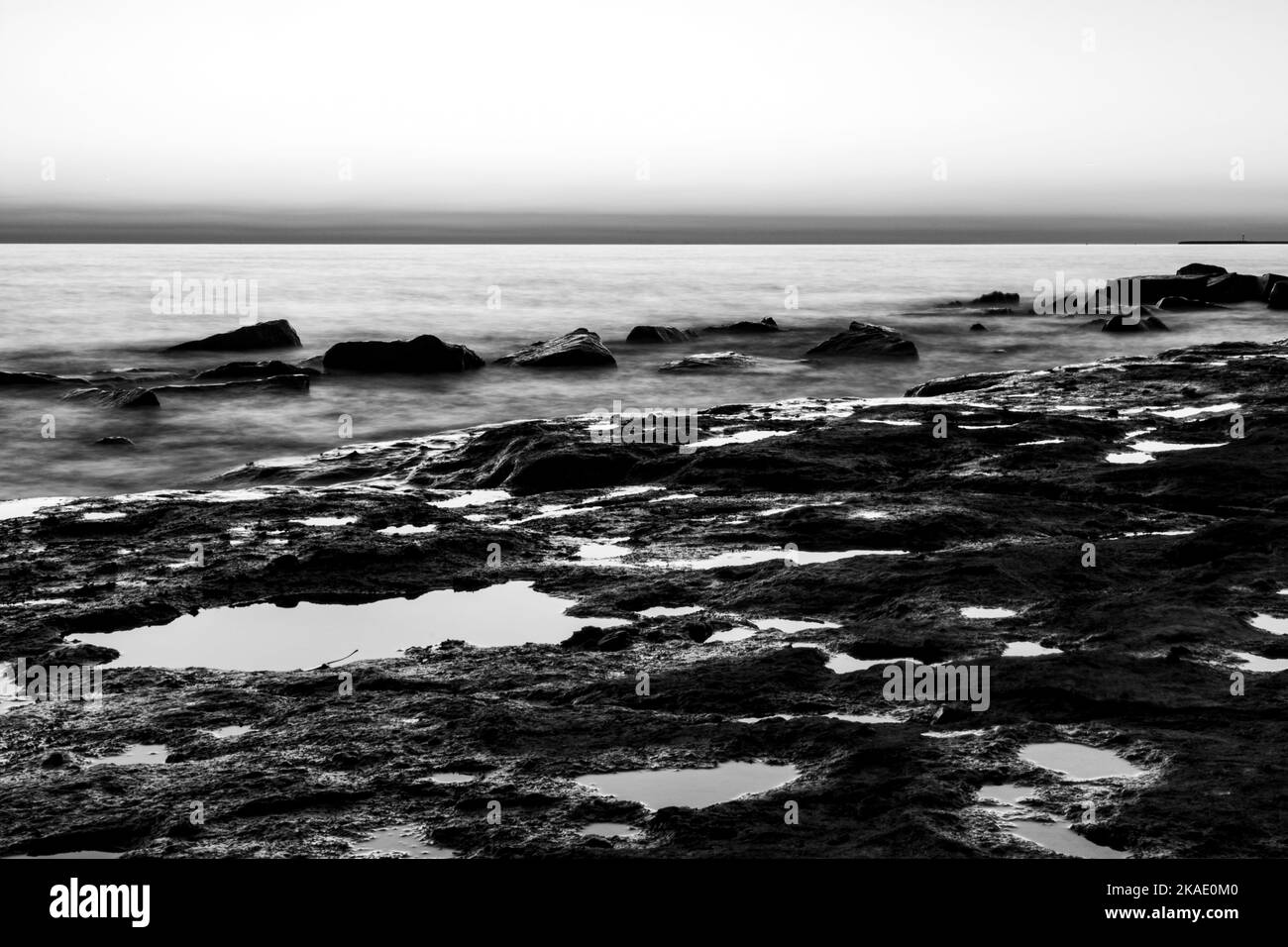 Black and white long exposure of a sunrise right next to a huge lake ...