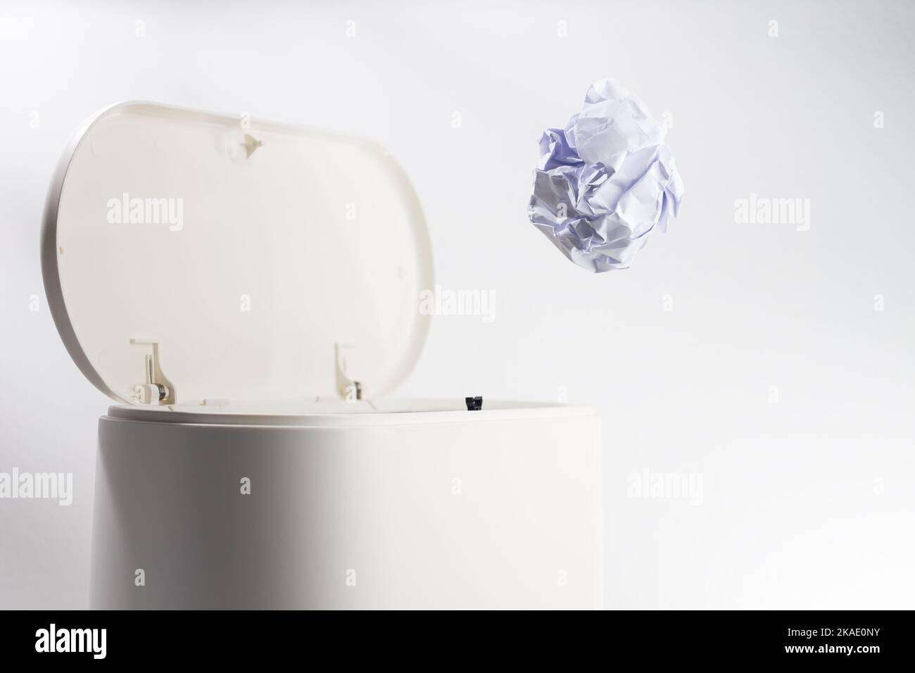 Throwing a paper ball into a white plastic garbage bin Stock Photo - Alamy