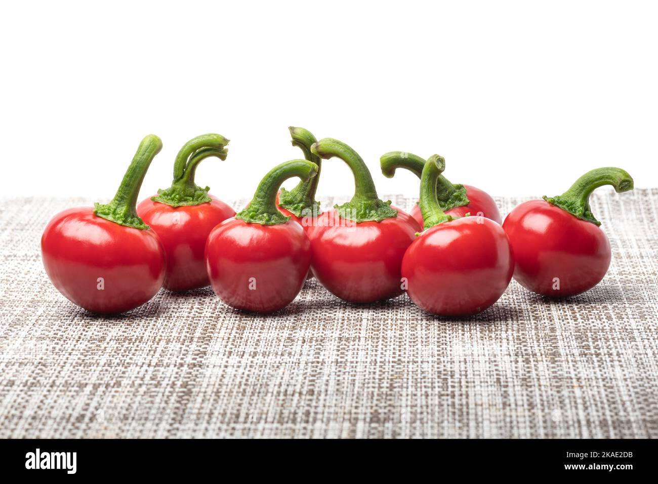 Bright ripe round red chili peppers cuts and seeds on cloth isolated ...