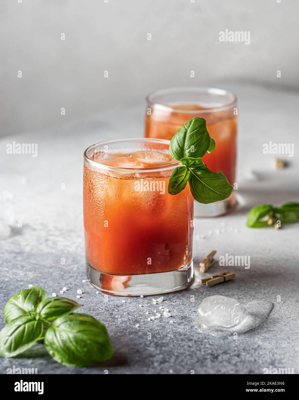 Tomato juice or Bloody Mary iced cocktail with bazil leaves in two ...
