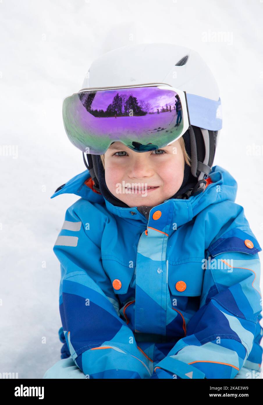 portrait child boy in a helmet, ski mask and warm jacket sits on the ...