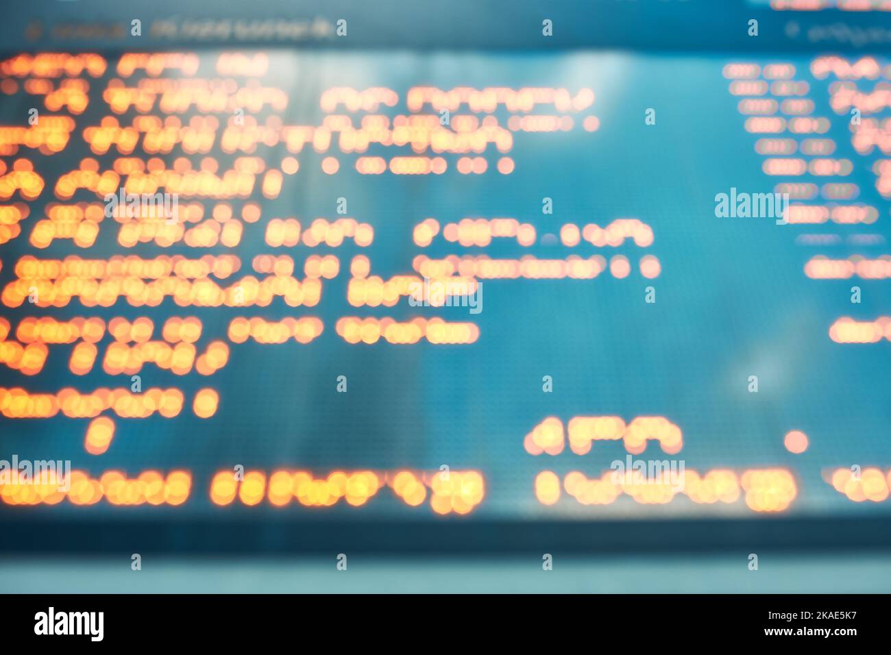 Out of focus blurred display screen with orange digital characters and ...