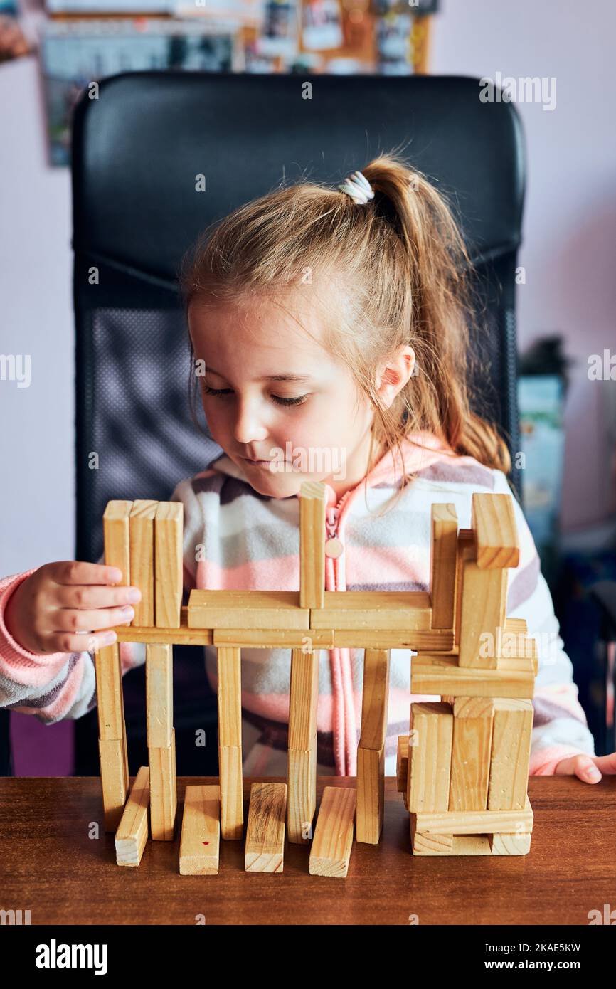 Little girl preschooler playing with wooden blocks toy building a tower ...