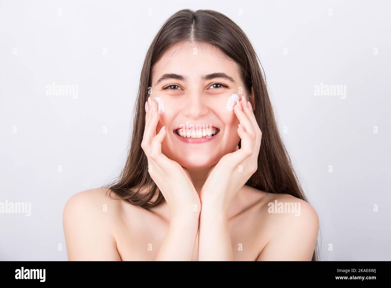 Happy Young Woman Spreads Moisturizing Face Cream On Her Cheeks