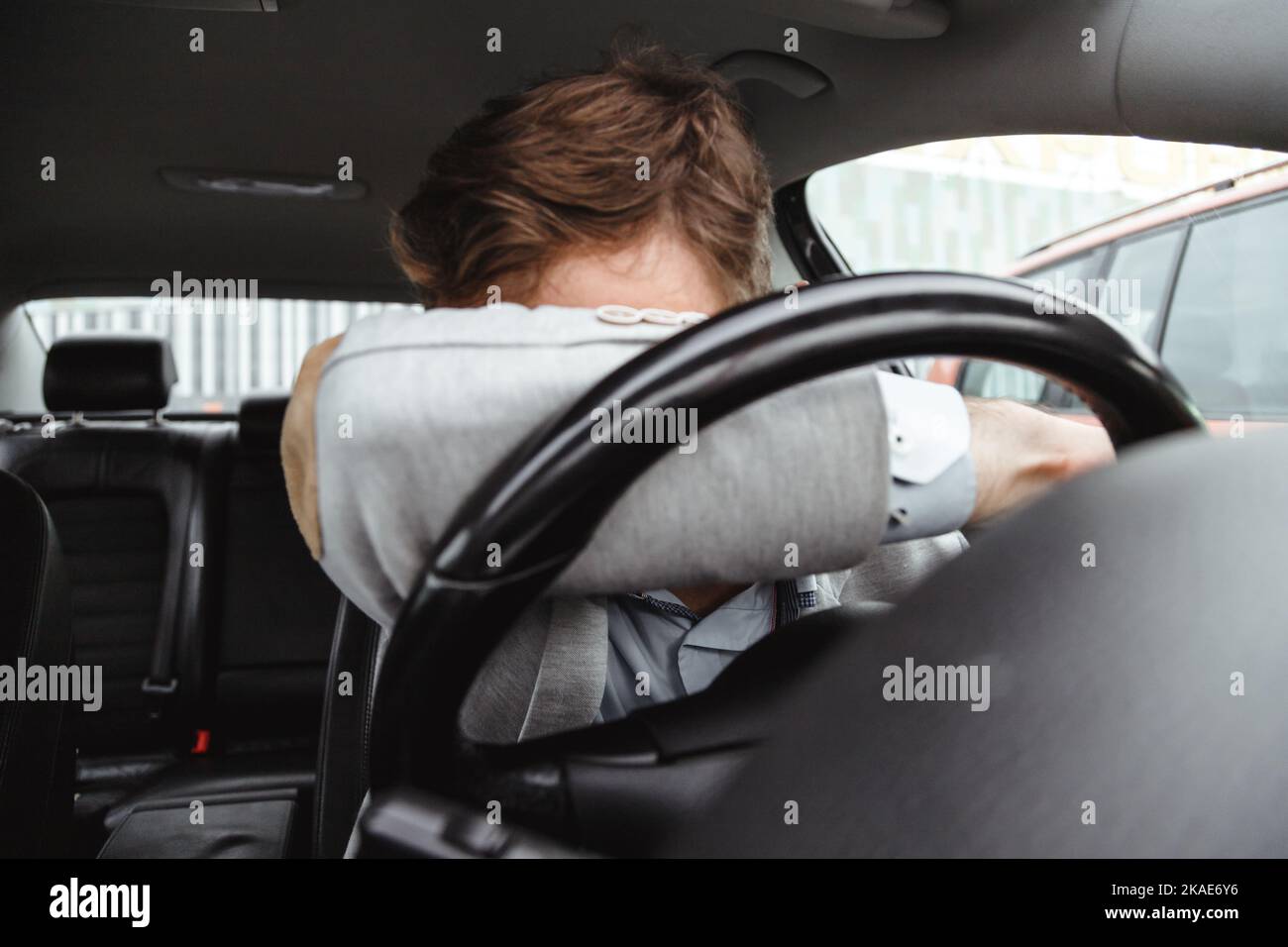 Exhausted driver in suit resting on steering wheel at parking Stock ...